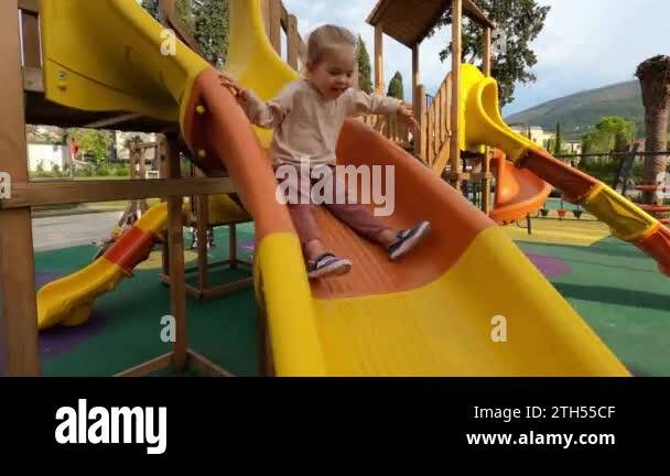 Little girl sticking out her tongue slides down the slide and gets to ...