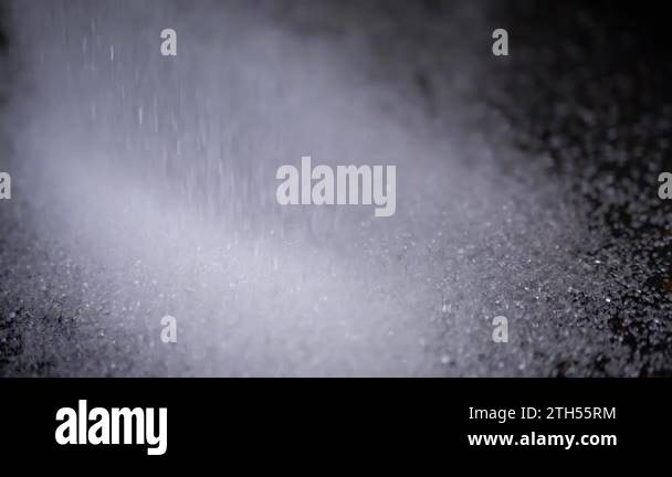 White Crystals of Granulated Sugar Fall on a Black Background in Slow ...