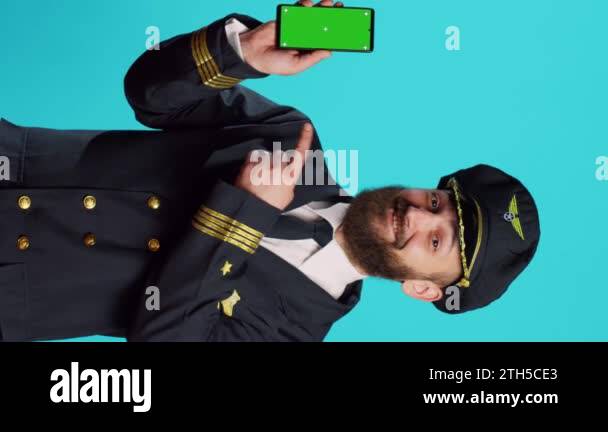 Vertical video: Positive aircrew captain showing phone with greenscreen ...
