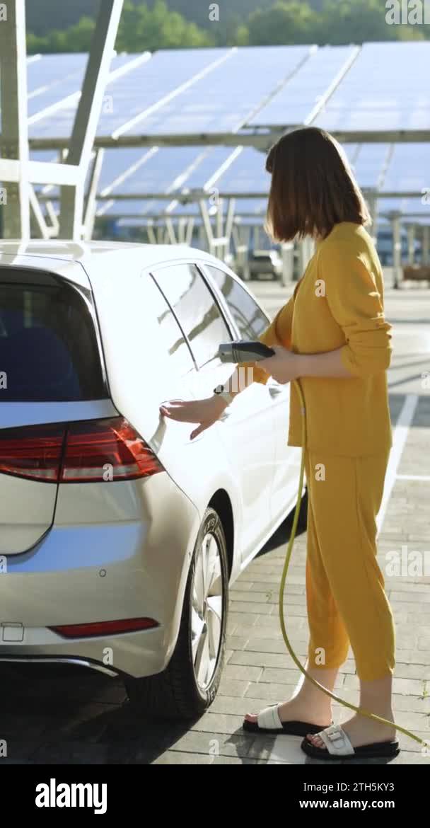 Vertical screen of caucasian female opening an electric car charging ...