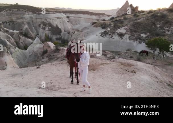Girl with white clothes with horse in Cappadocia. Sunset panoramic ...