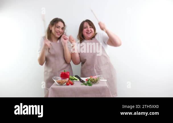 2 women dancing while preparing tasty and healthy food vegetarian food ...