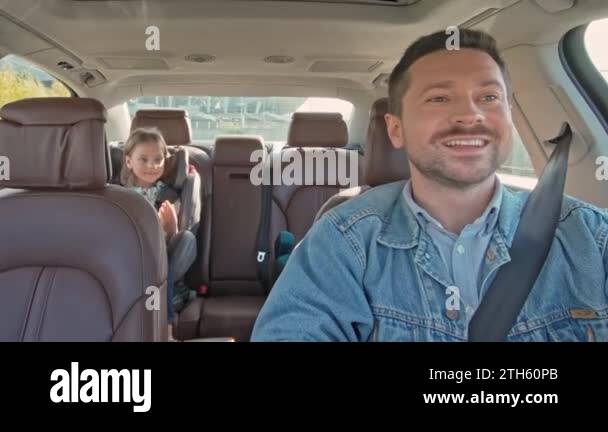 Young attractive dad driving car traveling with little cute girl ...