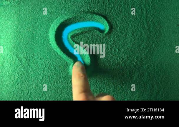 Hand drawing the Pound currency symbol in the Green Sand. Male hand ...