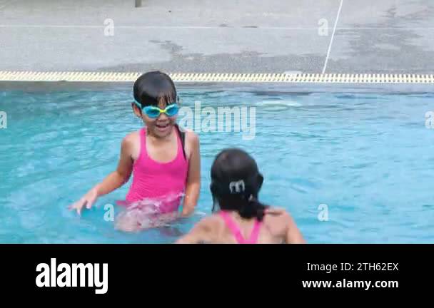 Happy little sisters are swimming and playing in outdoor swimming pool ...