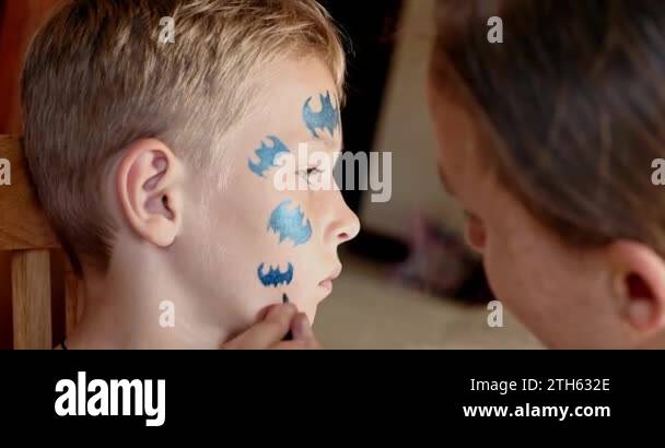 Child animator, artist's hand draws face painting to little boy. Child ...