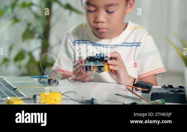 Asian kid boy assembling wheel into Arduino robot car homework, Little ...