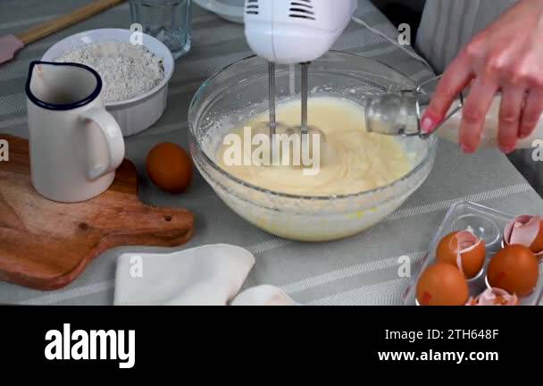 Female hands using hand mixer, cooking sweet dessert. Adding milk and ...