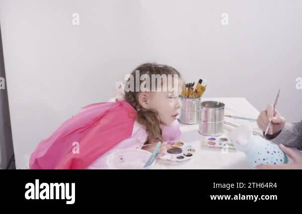 Little girl painting paper mache figurines with acrylic paint for her ...
