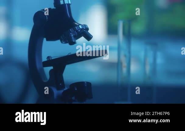 The camera moves across the microscope in a dark laboratory with soft ...