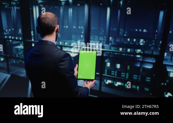 Data center technician holding tablet with green screen in server room ...