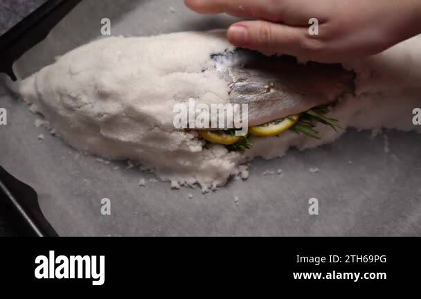 The chef sprinkles large amounts of salt on fresh fish with spices ...