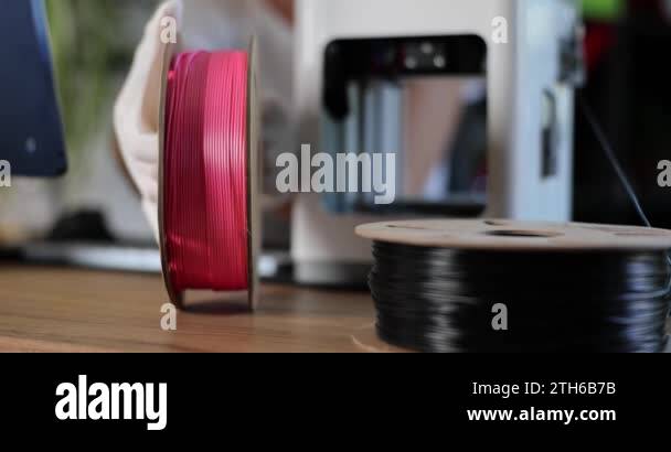 Engineer unwinds plastic for 3D printer closeup. Main types of plastics ...