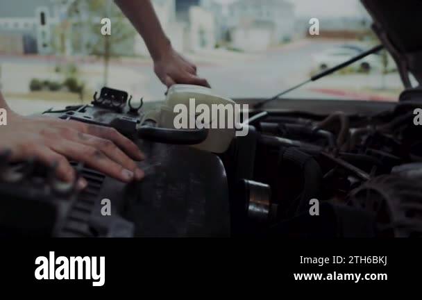 Woman in early 20s checking under the hood of a truck and going under the truck to find and fix ...
