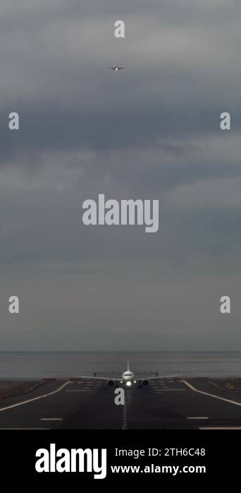 Vertical video - a passenger plane picks up speed, accelerating on a runway that starts at the ...