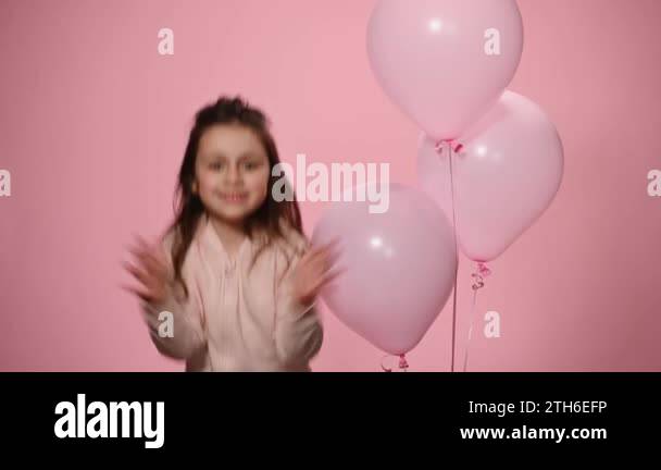 Lovely cheerful little girl in pink pastel wear, clapping her hands and ...