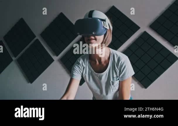 Young woman in a virtual reality headset plays a game at home. Emotional female using VR ...