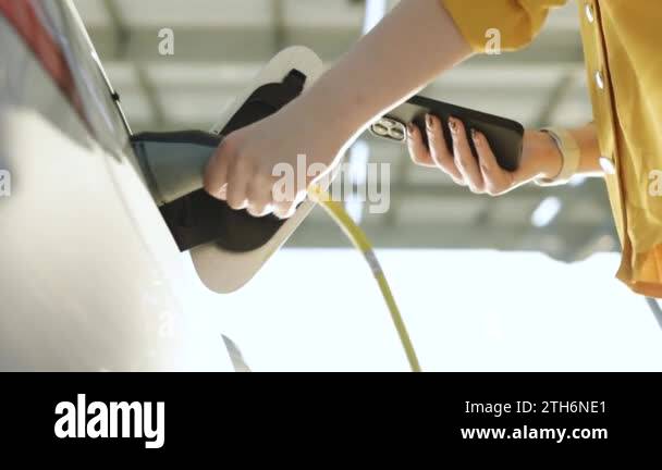 Woman unplugging electric car cable. Girl stopping charging using app ...