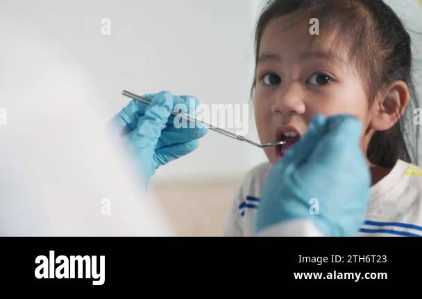 Dental kid health examination. Asian dentist making examination procedure for cute little girl ...