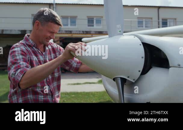 Aviator fixing airplane propeller smiling enjoying preflight process on ...