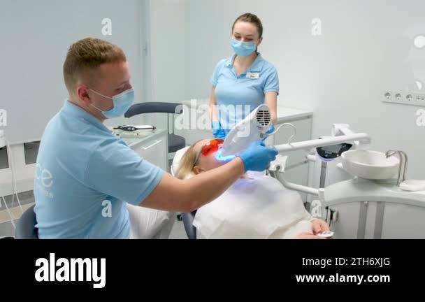 dental clinic teeth whitening woman lying under apparatus doctor and ...