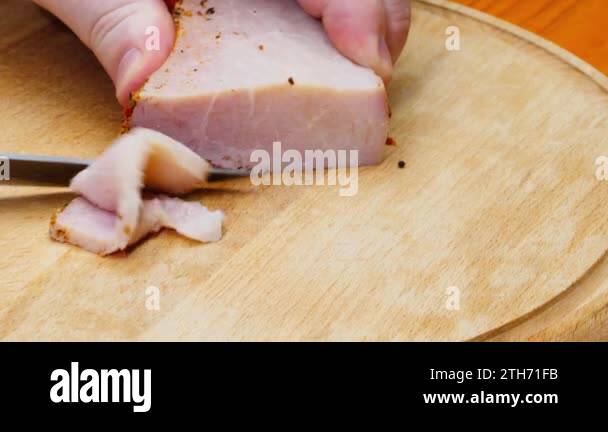 The chef cuts the ham. A man cuts fresh homemade smoked pork ham on a ...