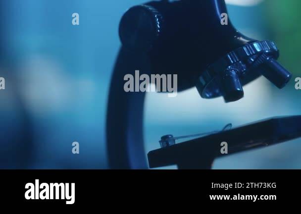 The camera moves across the microscope in a dark laboratory with soft ...