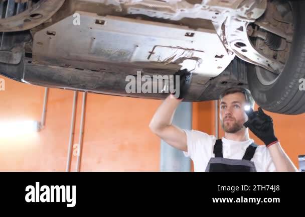 A car mechanic repairs the chassis of a car in a car service. The mechanic checks the chassis ...