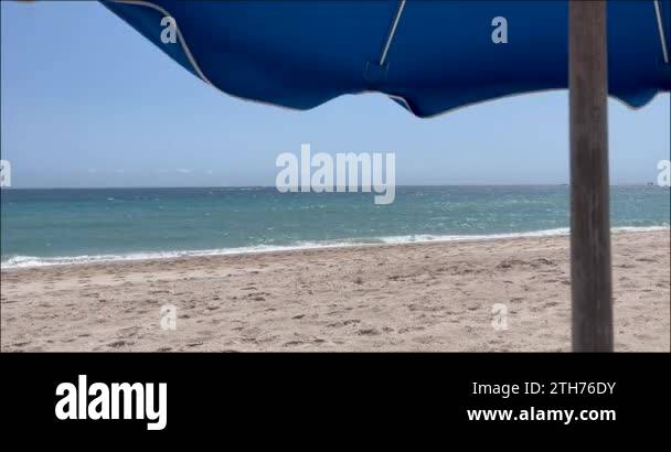 Wind whips a beach umbrella at a south Florida beachfront resort, with ...