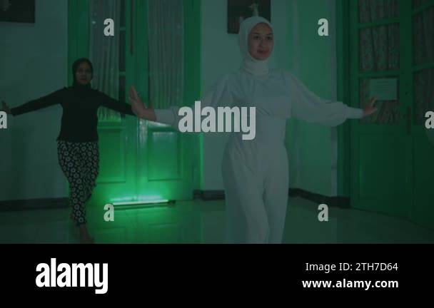 two Muslim women dance together very agilely in closed clothes in a ...