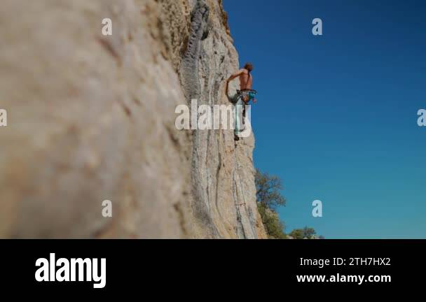 young powerful athletic man rock climber with long hair climbing on ...