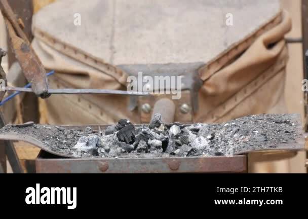 Medieval method of forging iron, the blacksmith forges an iron nail ...