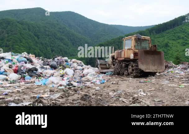 An old abandoned dump of unsorted garbage, a tractor on the landfill ...