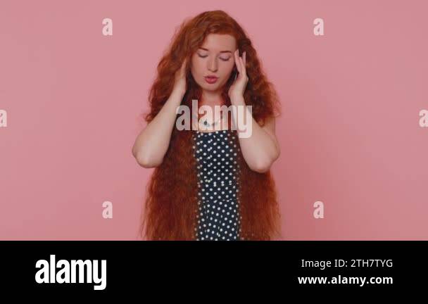 Redhead sleepy young woman in dress rubbing temples to cure headache ...
