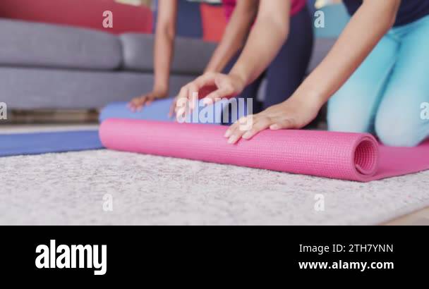 Video of midsection of diverse female friends rolling yoga mats at home ...
