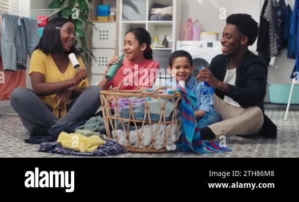 A family sits on the laundry room floor sorting clothes before putting ...