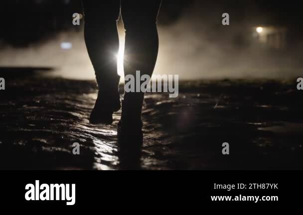 Creepy mysterious view of the legs of a man walking outdoors at night ...