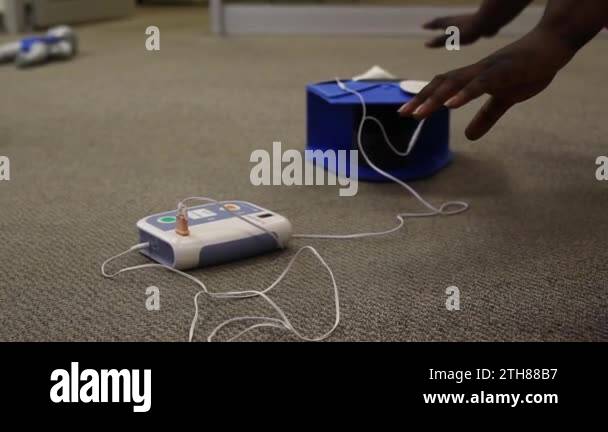 Staff is training to conduct first aid CPR with a dummy doll and AED ...