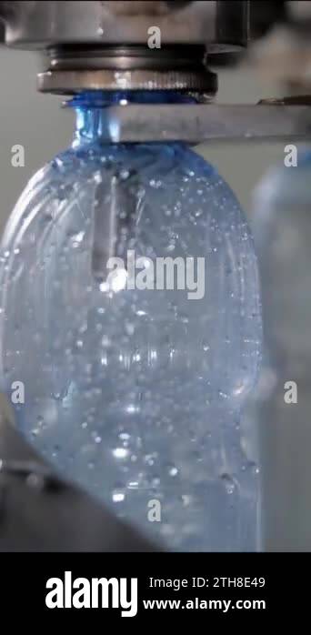 Vertical video. Close-up of pouring water into a plastic bottle with a ...