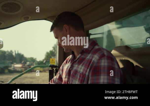 Tractor driver inside cabin checking machinery closeup. Focused farmer ...