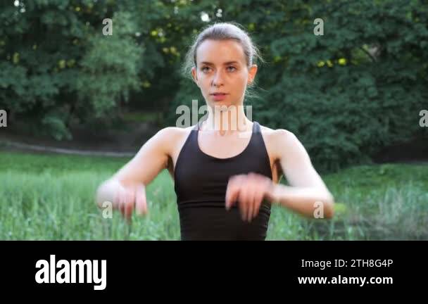Young blond sportswoman stretching arms before exercising in summer ...