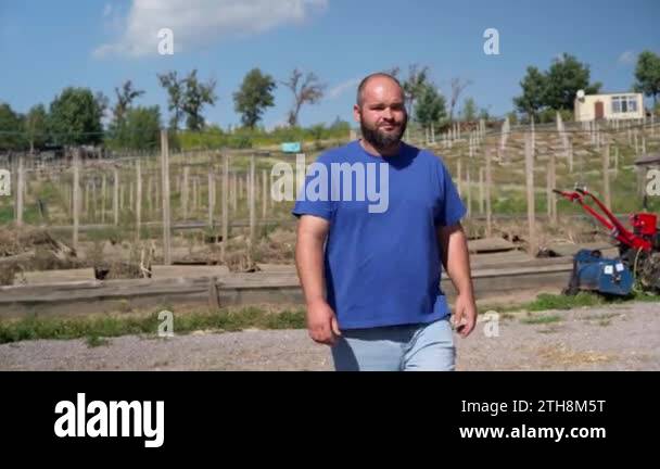 Medium shot portrait of Caucasian man walking on snail farm leaving. Confident bearded young ...