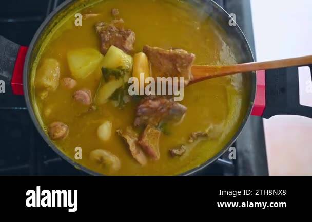 Handheld close up view of wooden ladle mixing typical Dominican creole ...