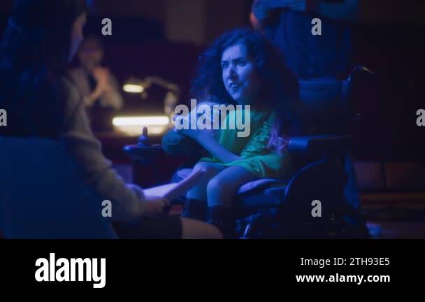 A disabled woman in a wheelchair on stage with colleagues playing a ...