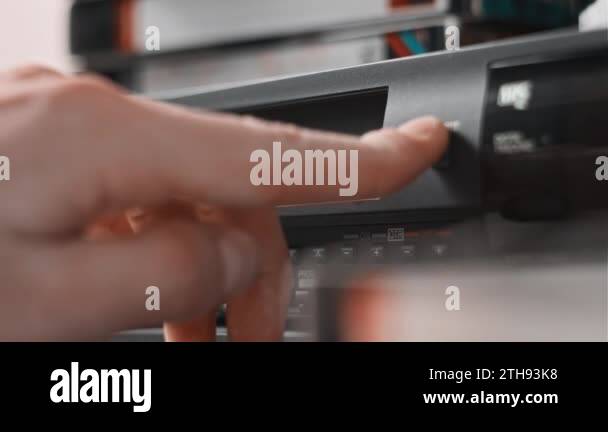 Eject VHS tape cassette from VCR player. Male hand pulls out VHS from a ...