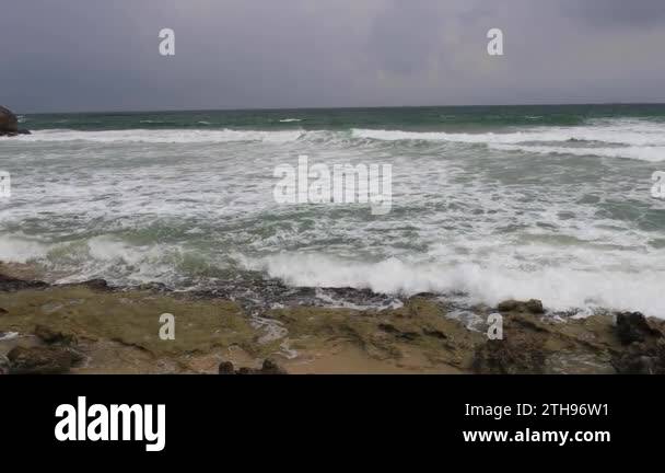 Beach with waves on a rough sea. Sea waves impact rocky on the beach ...