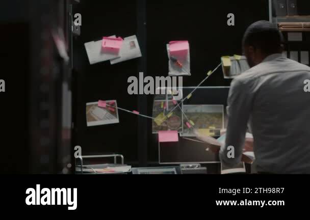 Professional police officer hanging clues on wall map to conduct ...