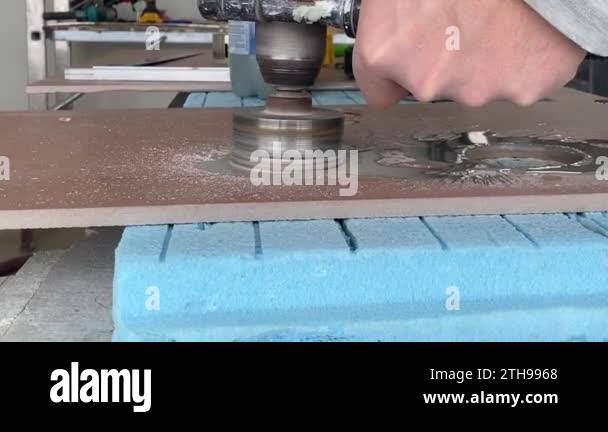 Worker tiller drills round hole in porcelain tile with a diamond core ...