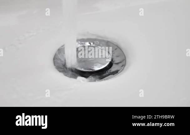 water flows down in sink drain hole. slow motion water drain in ceramic ...