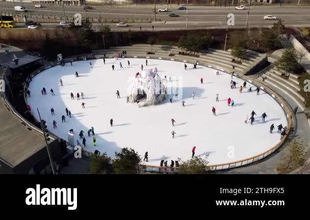 City ice skating rink in open air and road bridge in city. Aerial drone ...